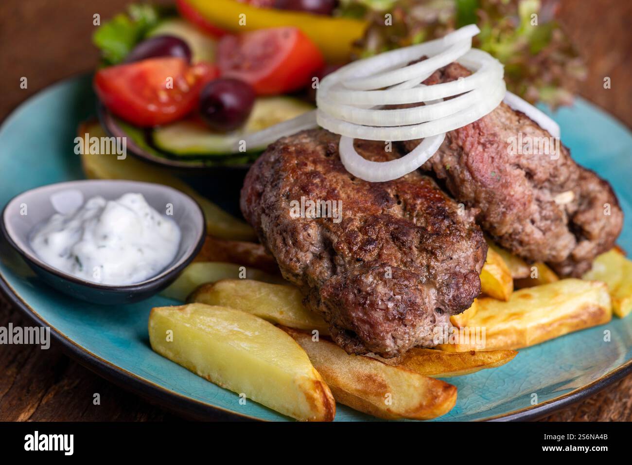 Greek bifteki with salad and French fries Stock Photo - Alamy