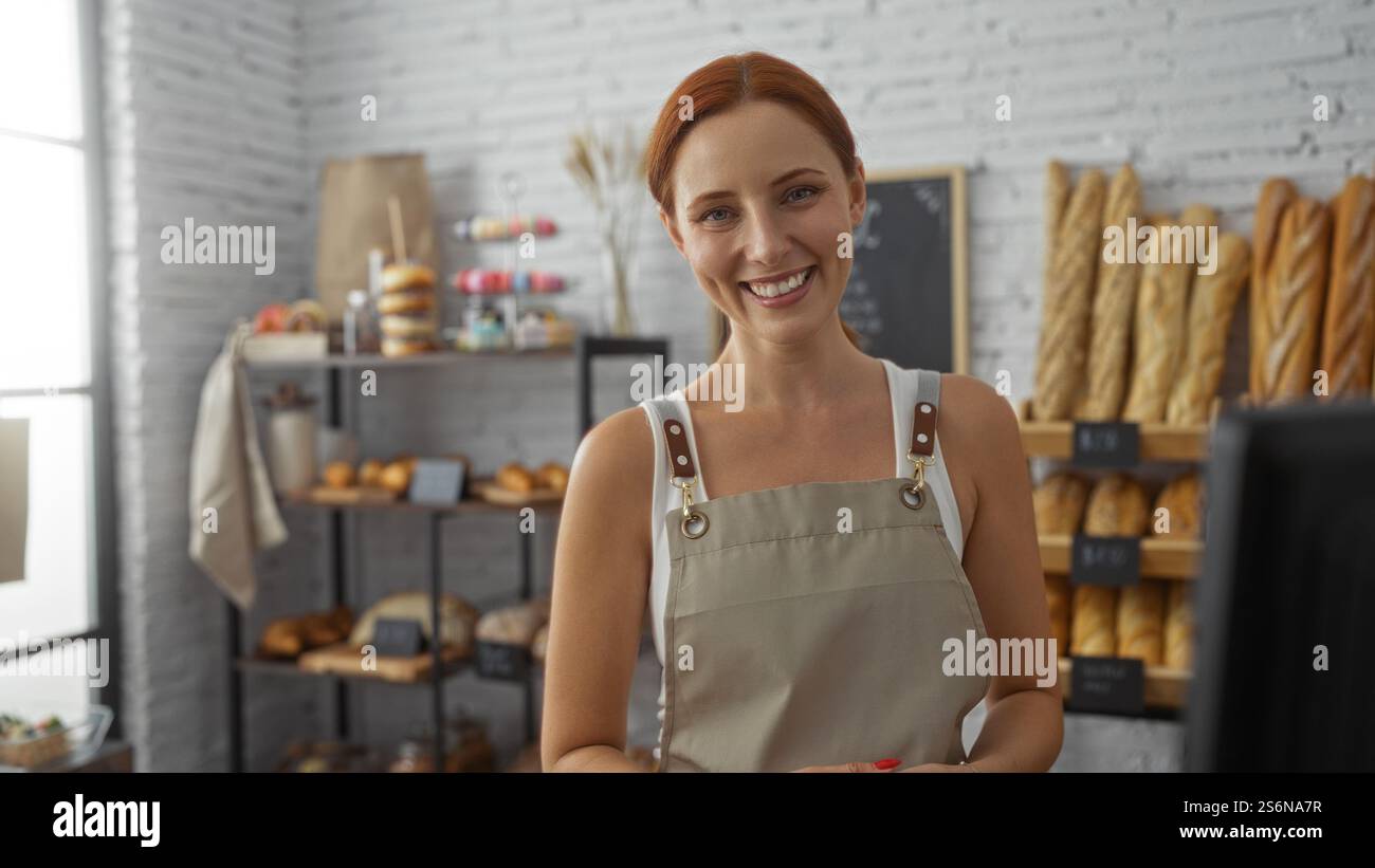 Young woman working in a bakery shop with an apron smiling at the ...