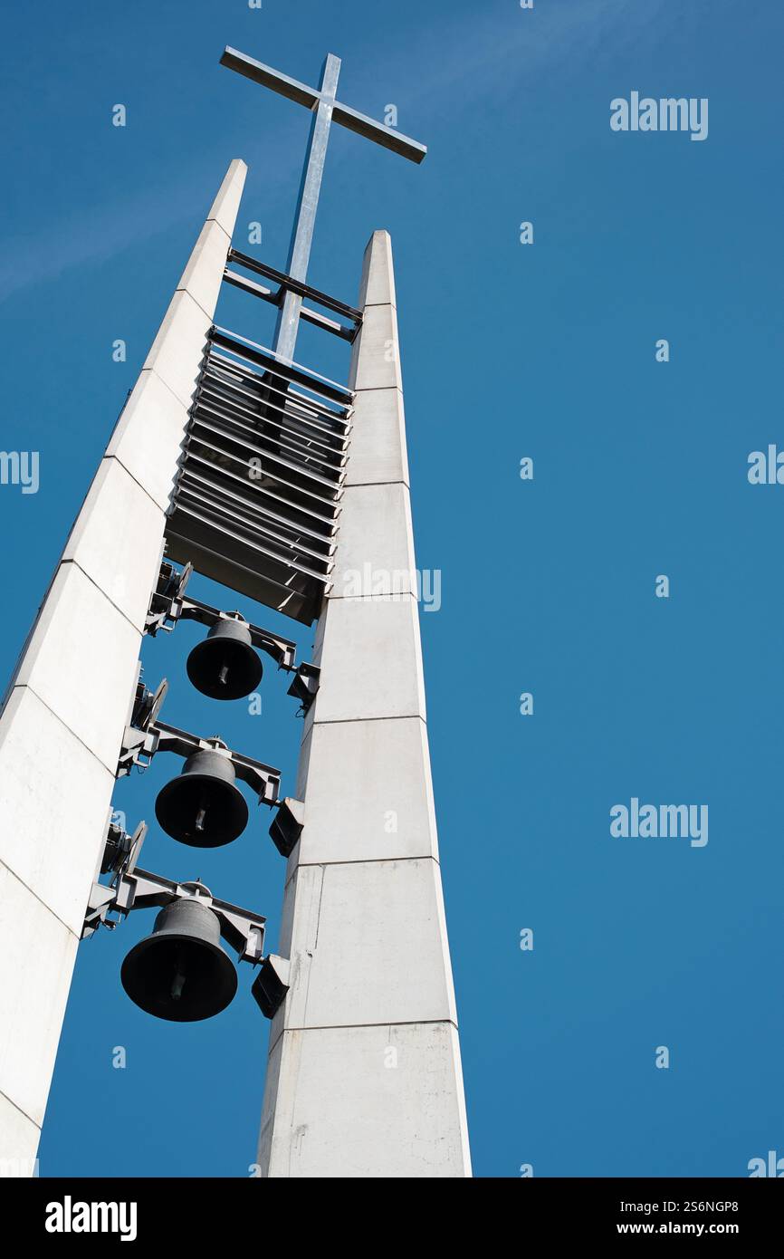 Modern church bell tower with blue sky in background. Three bells with ...