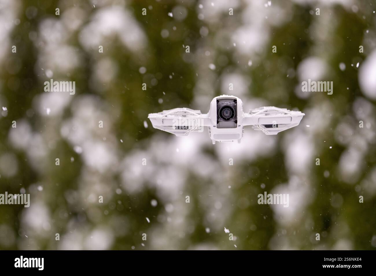 A white drone with a camera is flying through the snow. The drone is ...