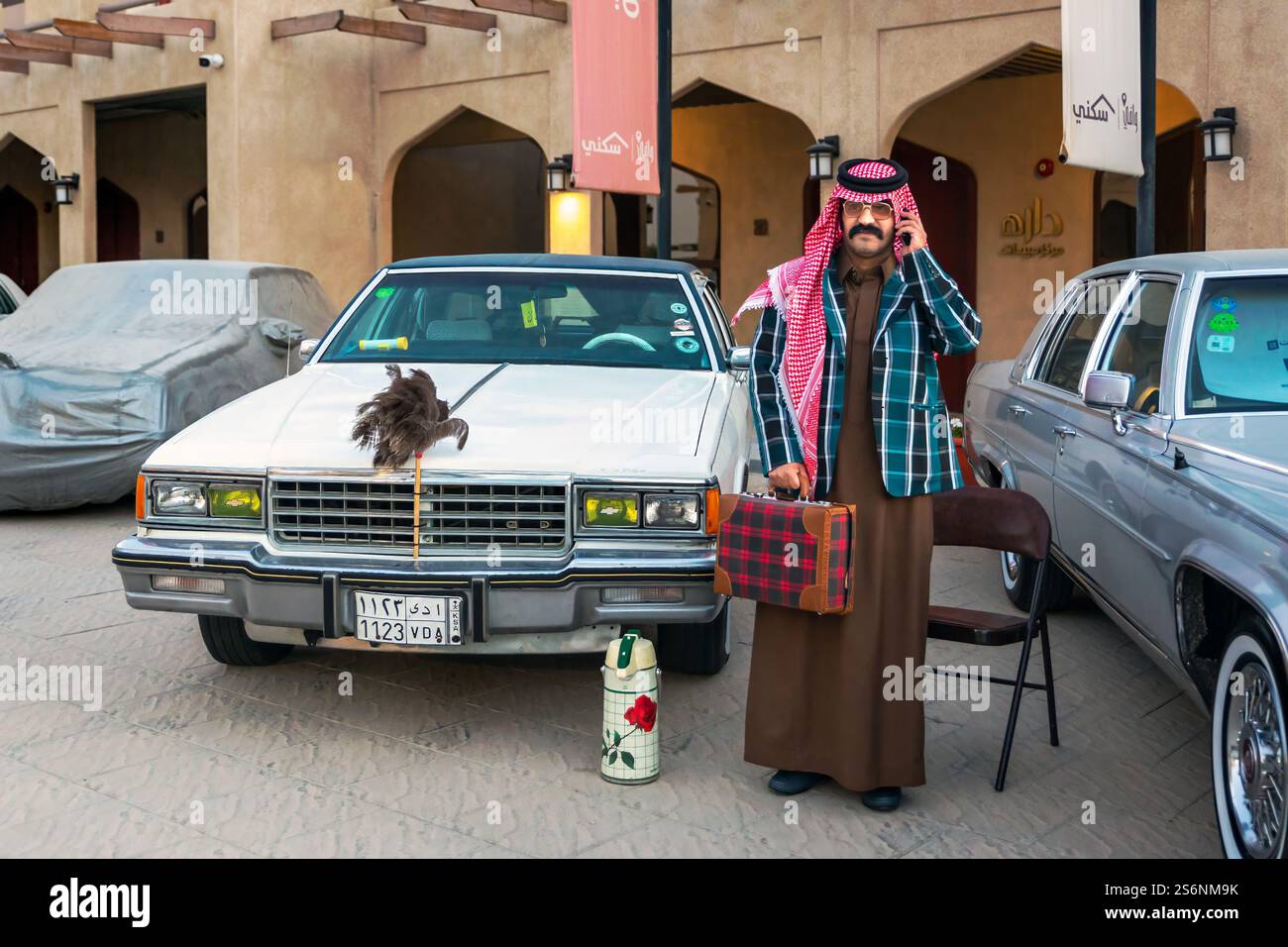 An Arab man wearing traditional attire next to a classic old car at the ...