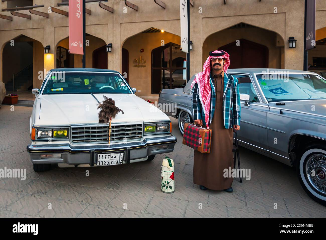 An Arab man wearing traditional attire next to a classic old car at the ...