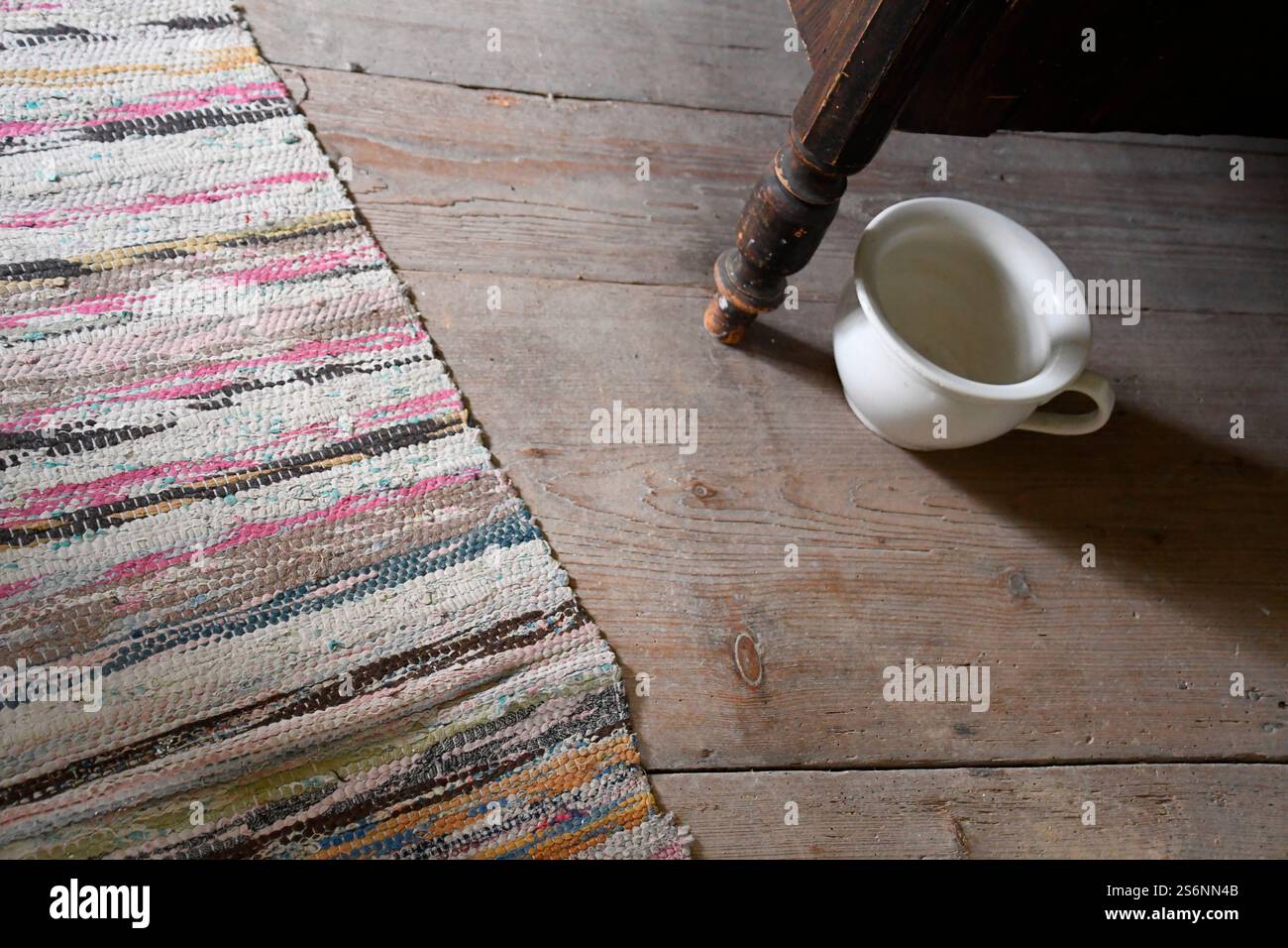 Enameled chamber pot stands on wooden floor next to bed leg Stock Photo ...