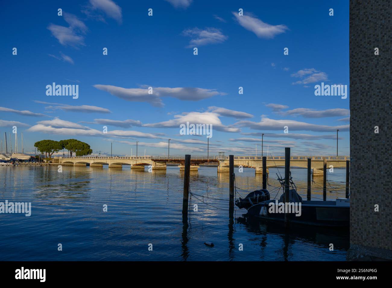 A calm harbor scene with a bridge spanning the water. A small fishing ...