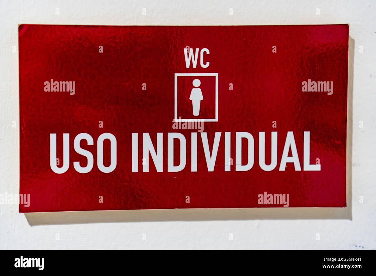 A red sign with a white border and a woman's head on it. The sign says ...