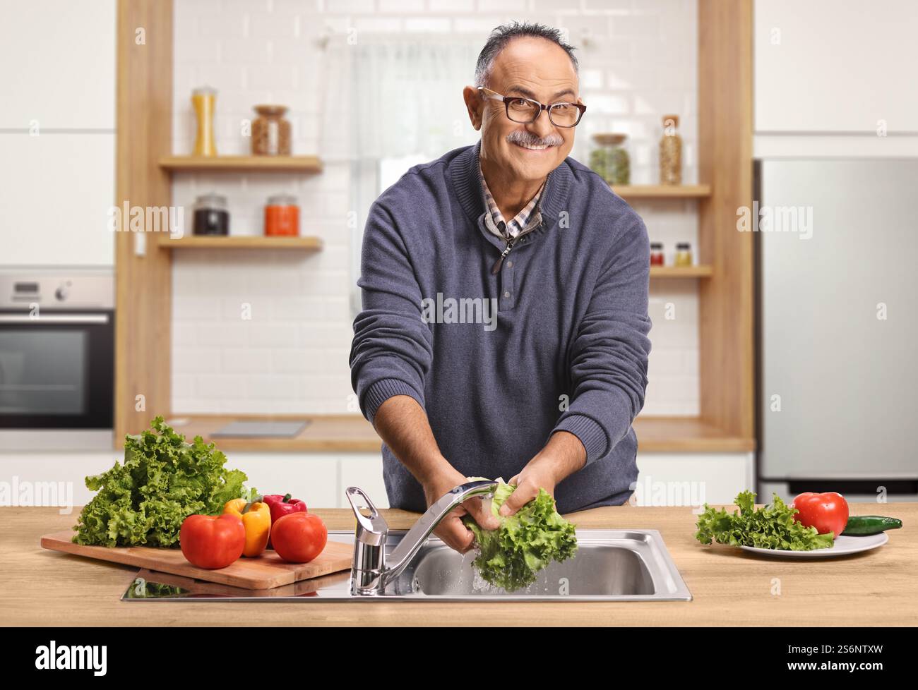 Mature man washing vegetables in a kitchen Stock Photo - Alamy