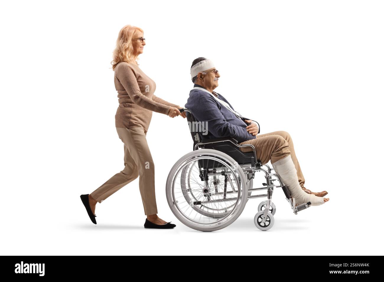Woman pushing a man in a wheelchair with head, arm and leg injury ...