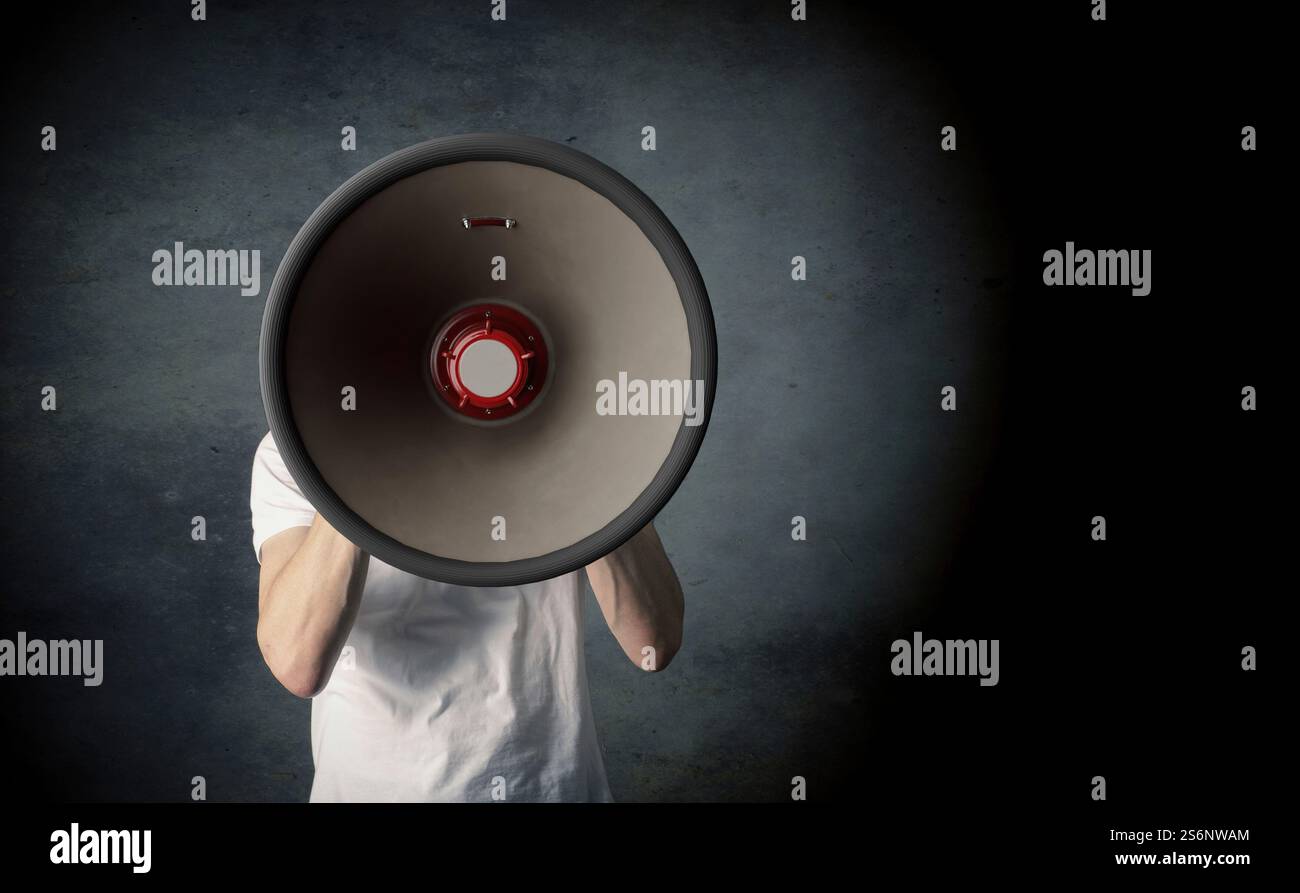 Young man holding a big megaphone, speaking loud concept on a dark ...