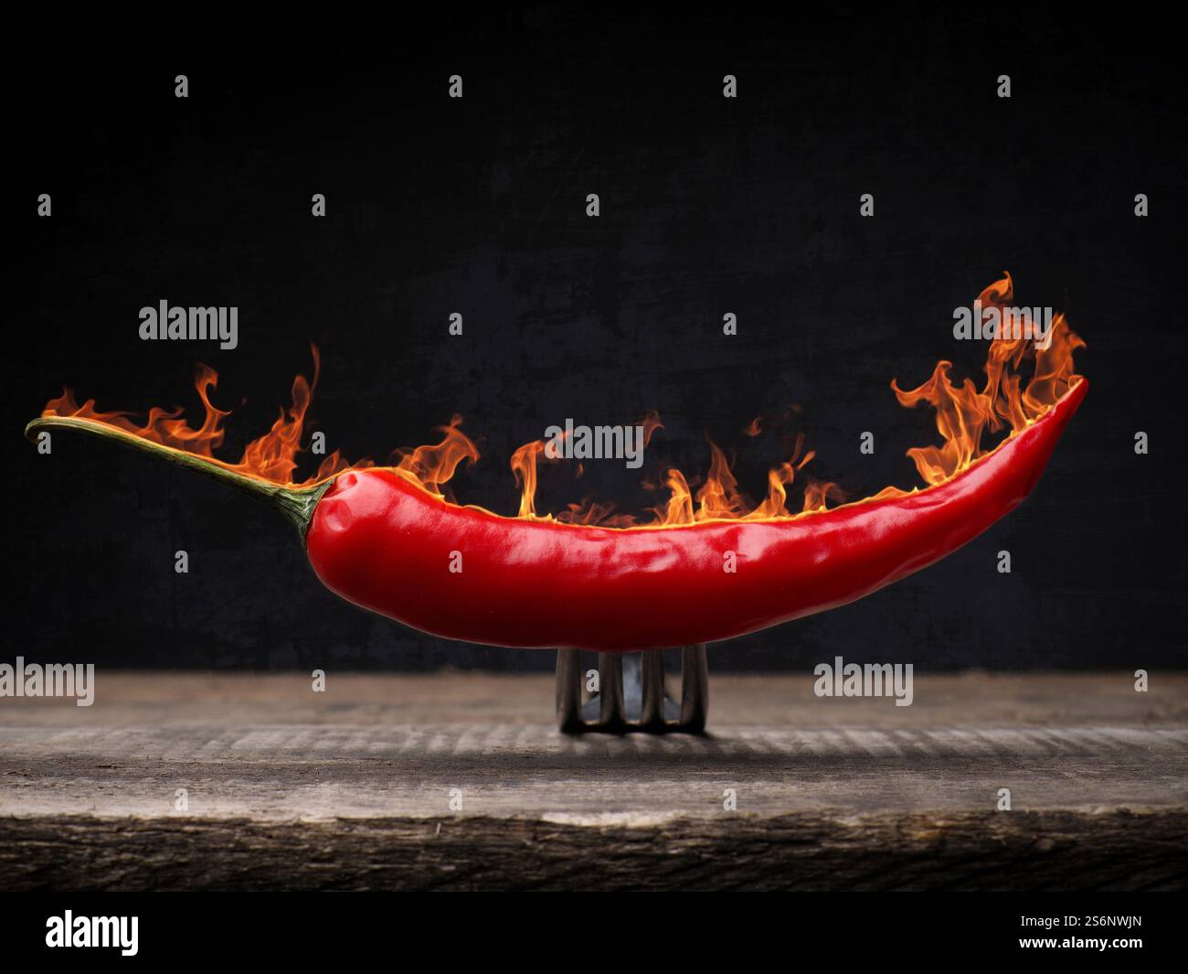 Red hot pepperoni with flames on an old table Stock Photo - Alamy