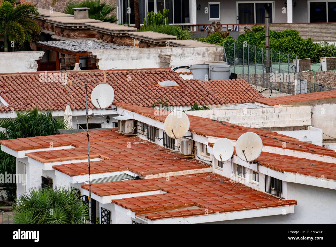 A row of houses with red roofs and white siding. The roofs are covered ...