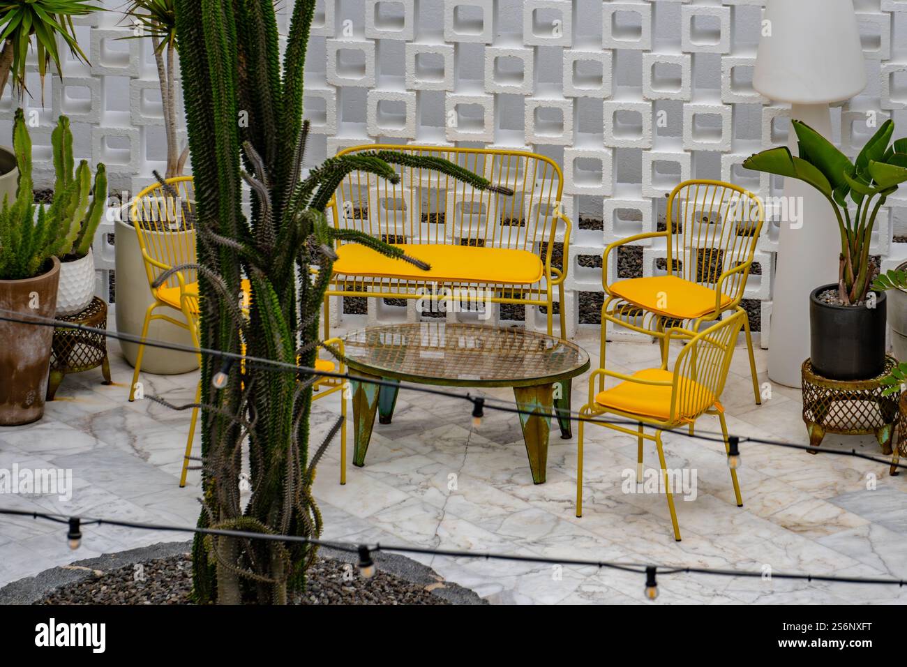 A yellow patio set with a white wall behind it. The chairs are yellow ...