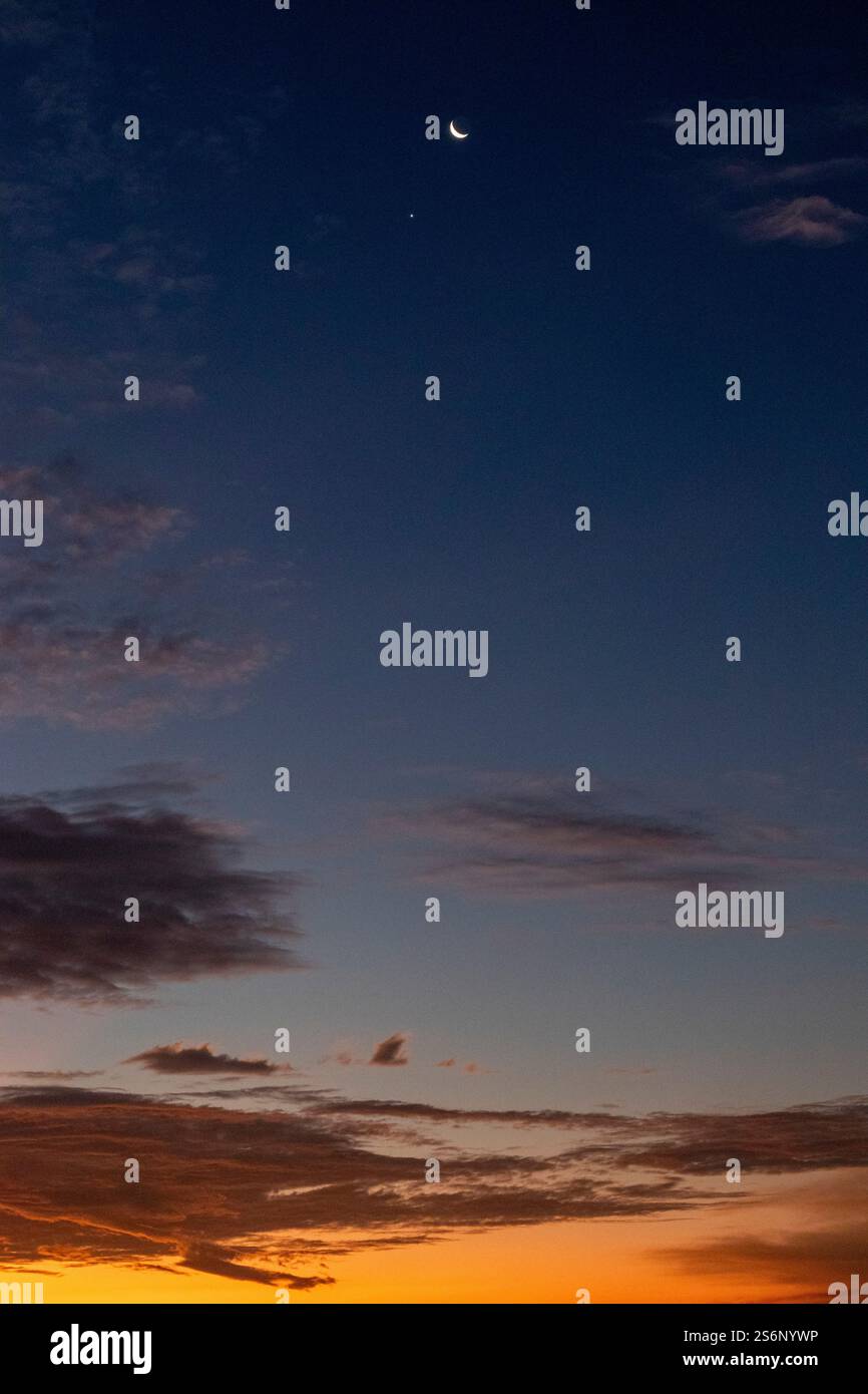 A crescent moon and a bright star in a colorful twilight sky with ...