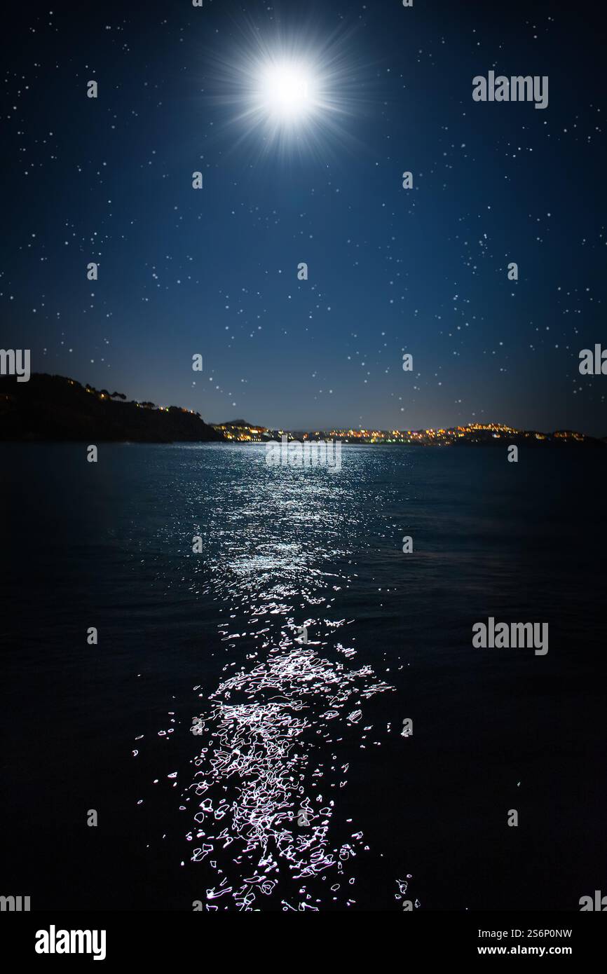The full moon at night is reflected on the sea at a seaside resort in ...