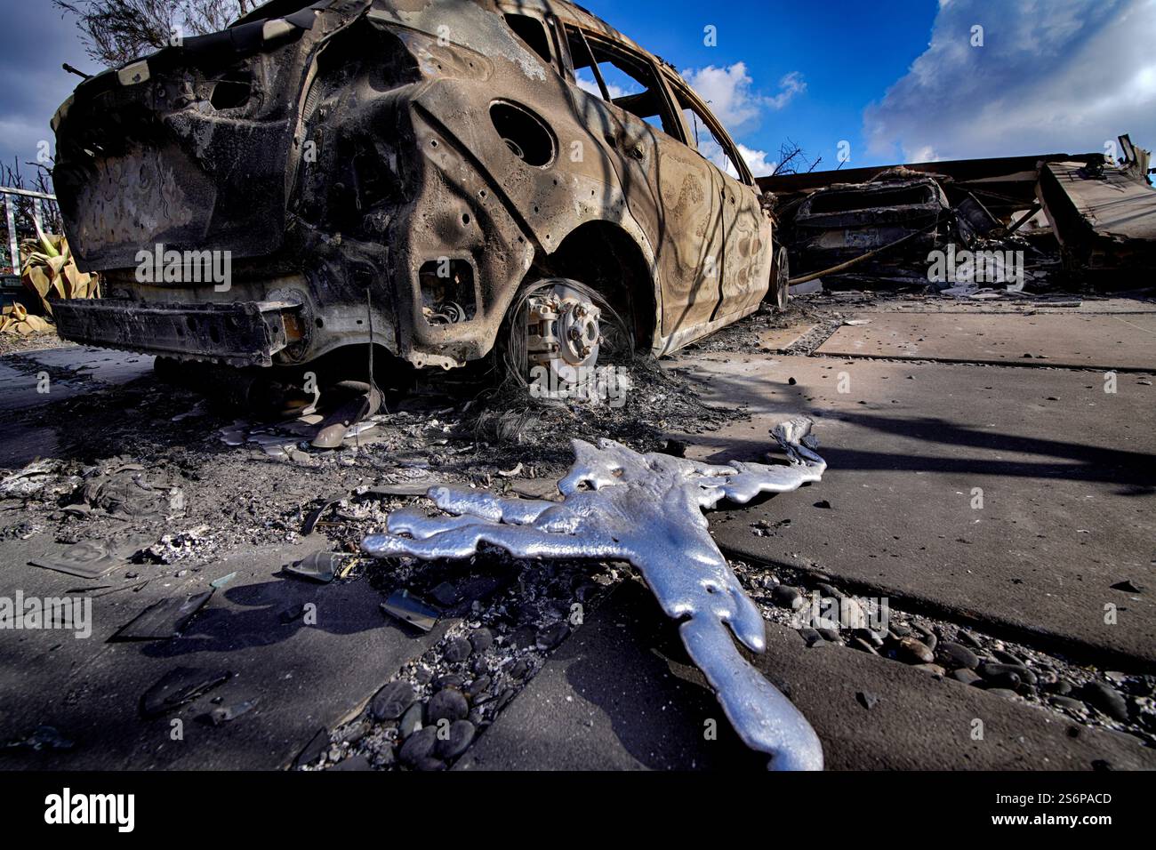 Melted metal and burned out cars sit destroyed in a driveway of a home ...