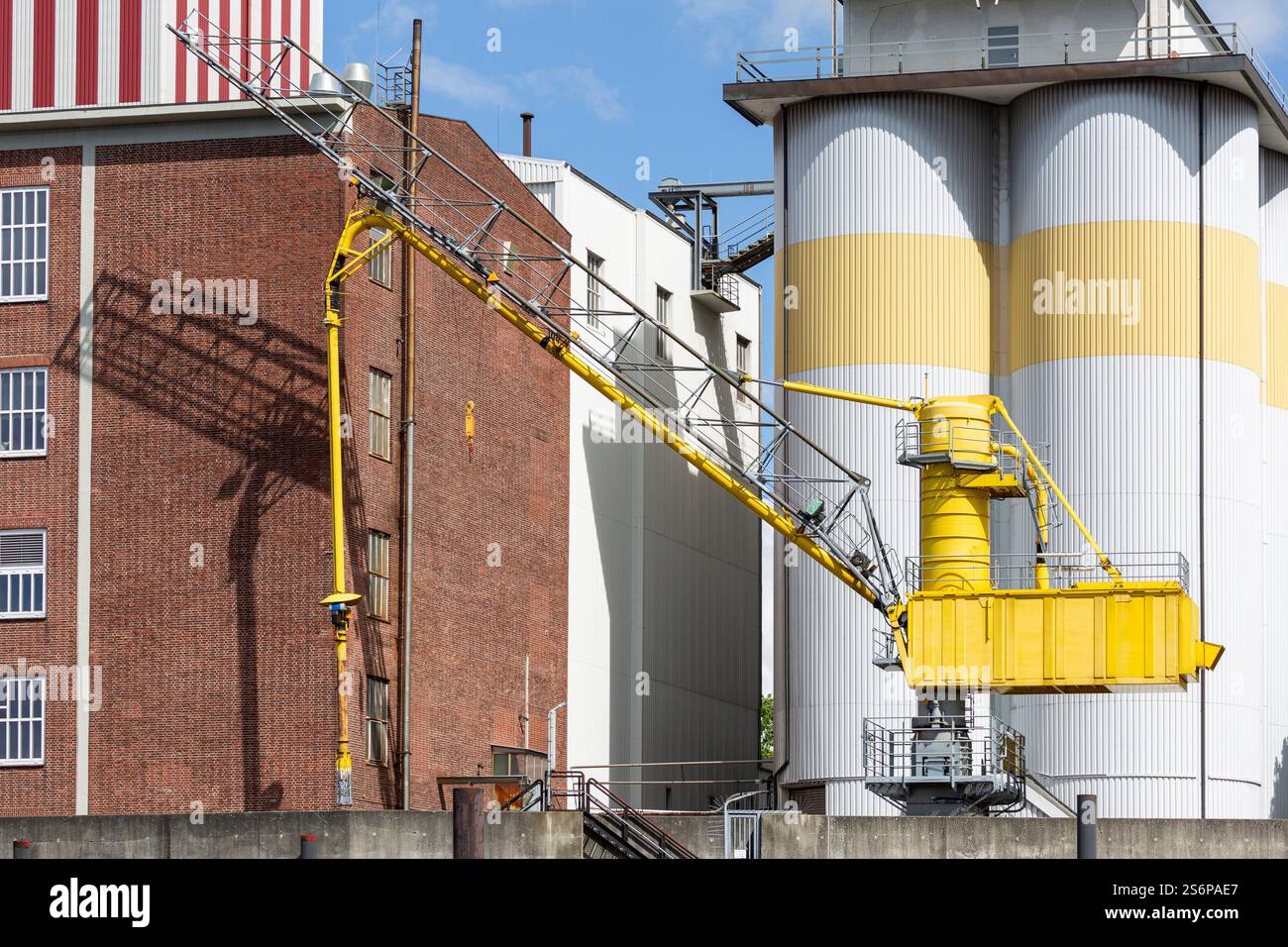 Yellow crane for unloading cargo in front of silos in the port of ...