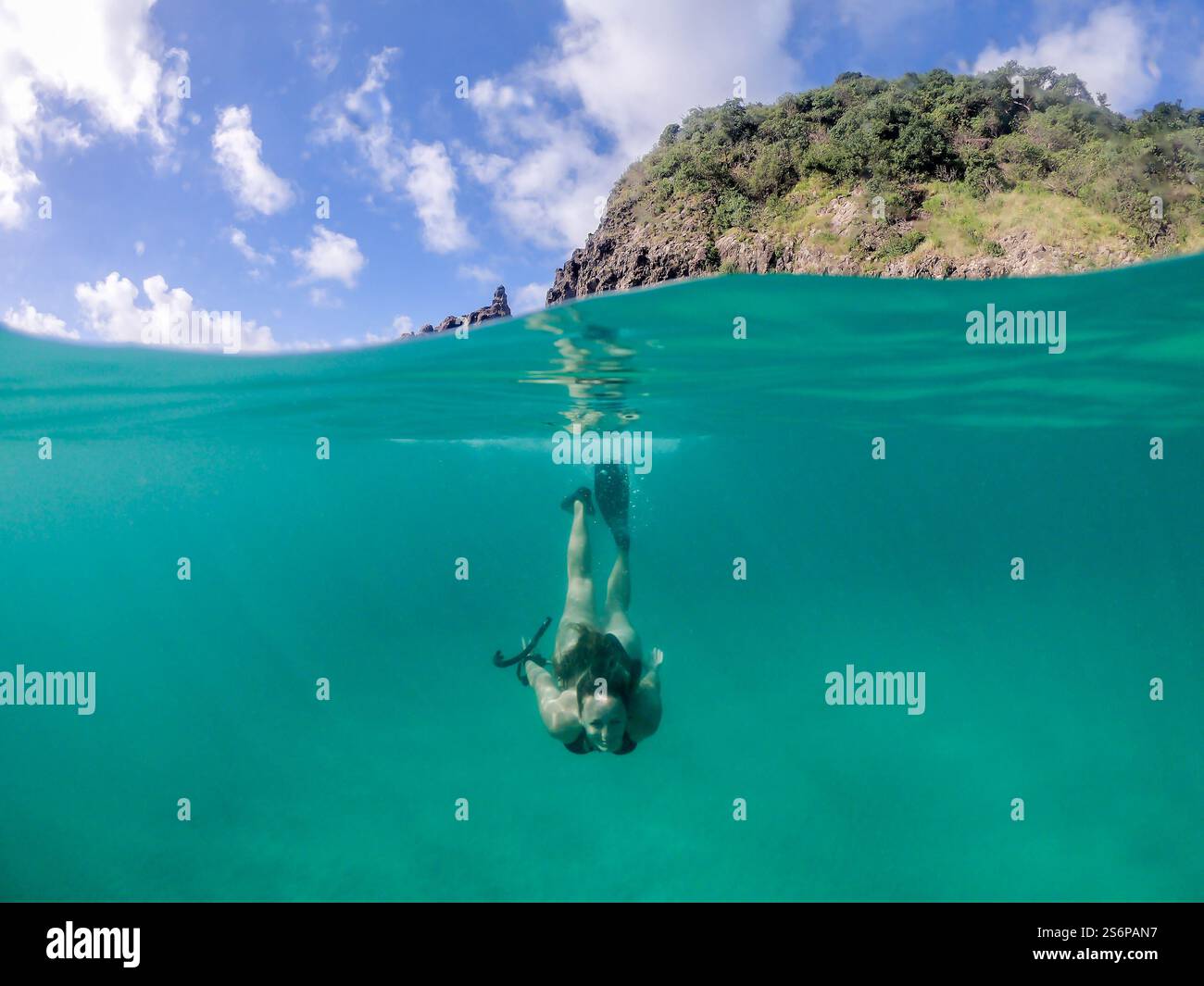 A surface split photo showing a woman swimming underwater at a beach in ...