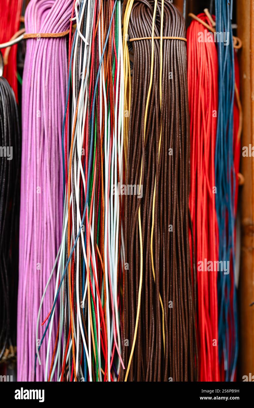A bunch of colorful cords are hanging from a rack. The cords are of ...