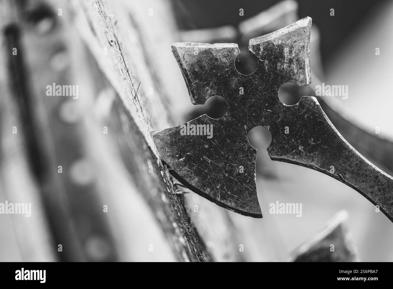 A black and white photo of a rusty axe with a cross on it. The axe is ...