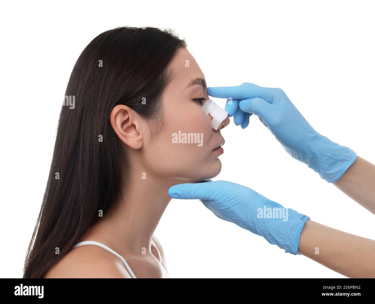 Doctor checking patient's nose after plastic surgery operation on white ...