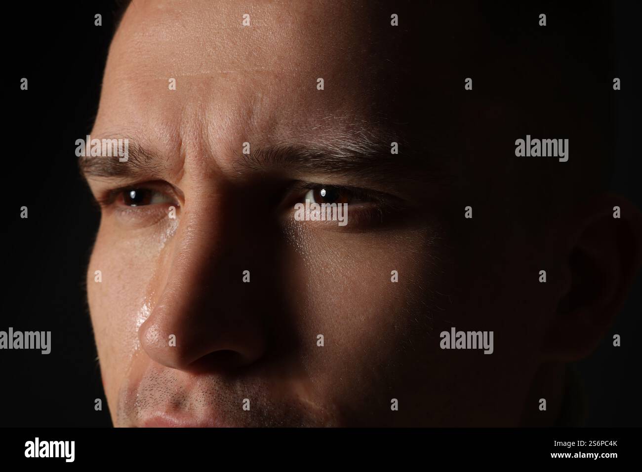 Distressed young man crying on black background, closeup Stock Photo ...