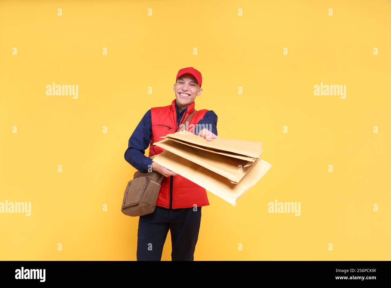 Happy postman with bag giving envelopes on yellow background Stock ...