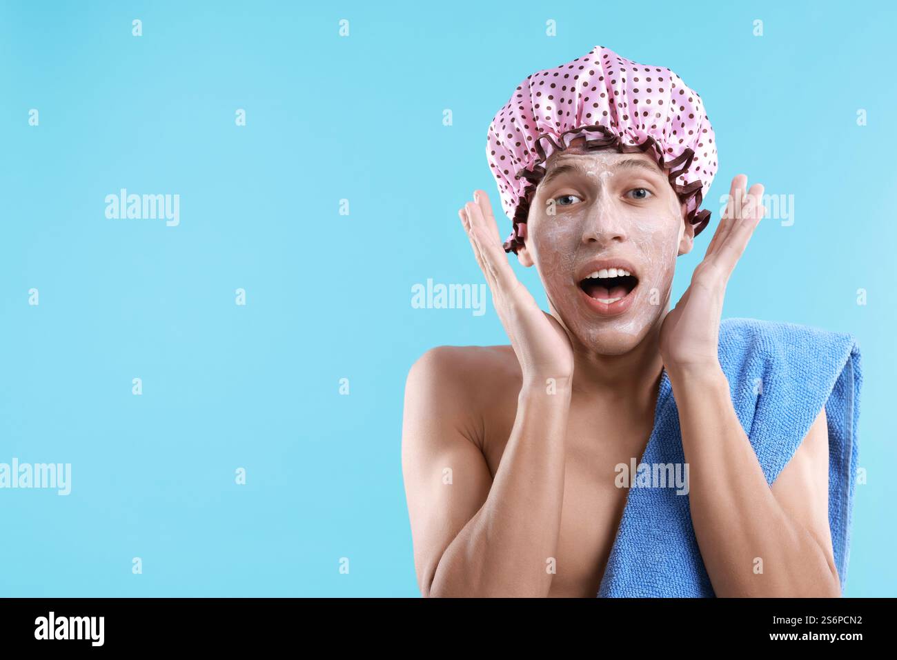Man in shower cap with cream on his face against light blue background ...