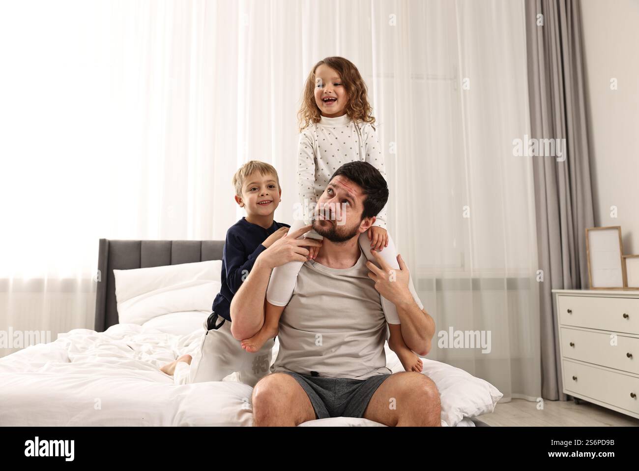 Overwhelmed father and his playful children on bed at home Stock Photo ...