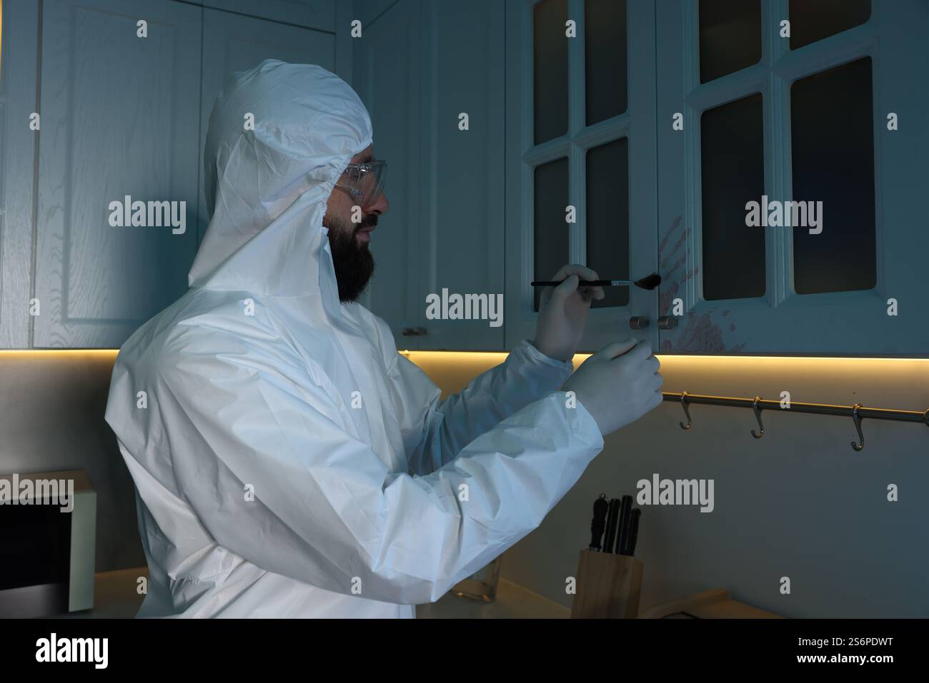 Forensic expert taking fingerprints from cupboard with brush at crime ...