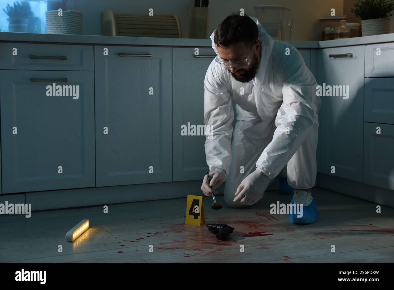 Forensic expert taking fingerprints with brush from gun at crime scene ...