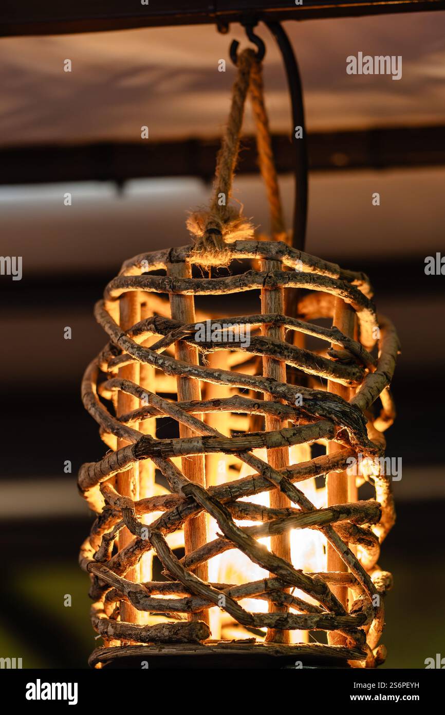 A lighted lantern hanging from a rope. The lantern is made of wood and ...