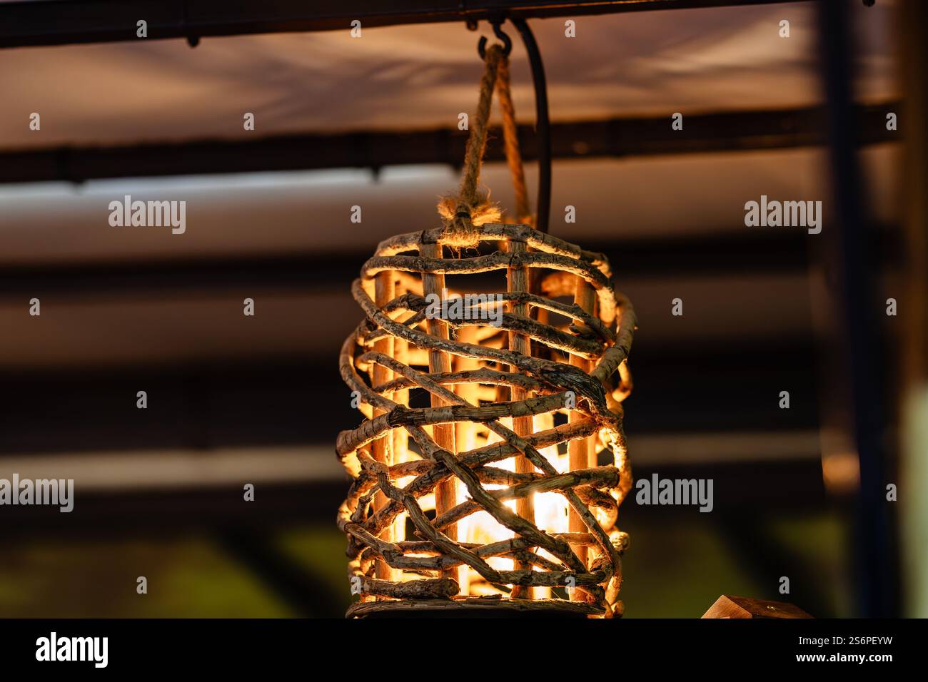 A lighted lantern hanging from a rope. The lantern is made of wood and ...