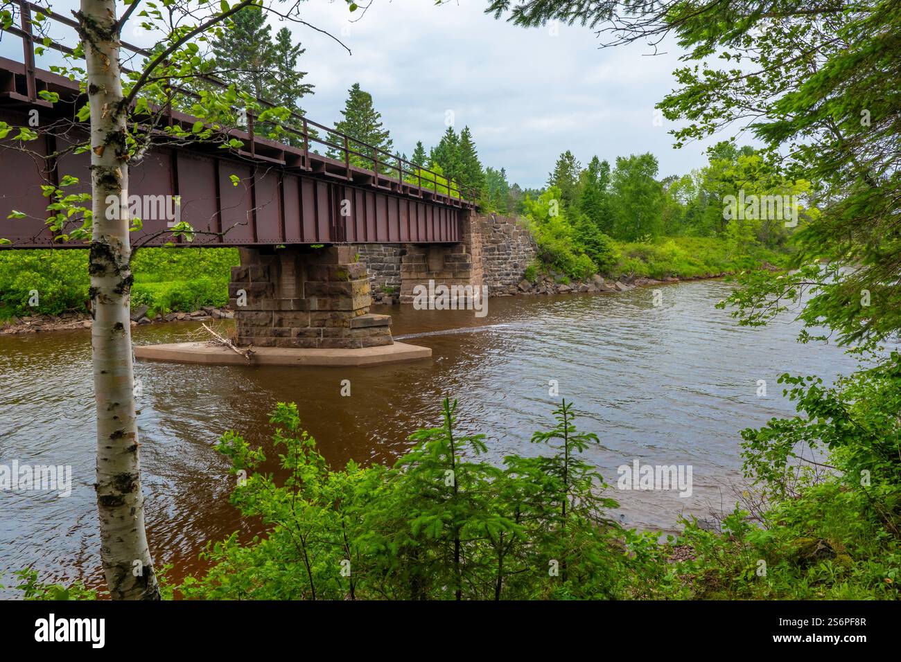 A steel bridge, supported by concrete and stone blocks, over a river in ...