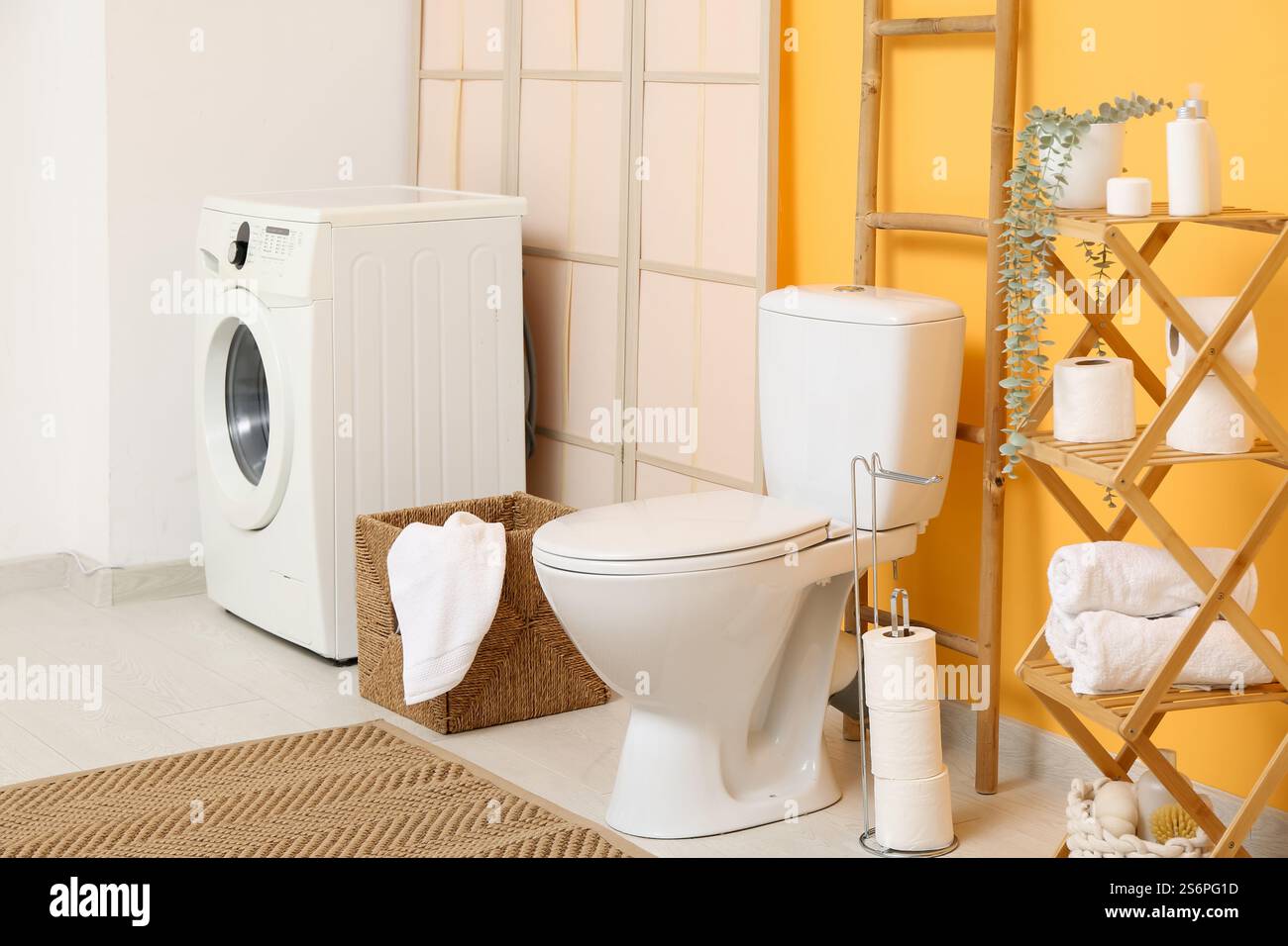 Interior of restroom with toilet bowl, washing machine and shelving ...