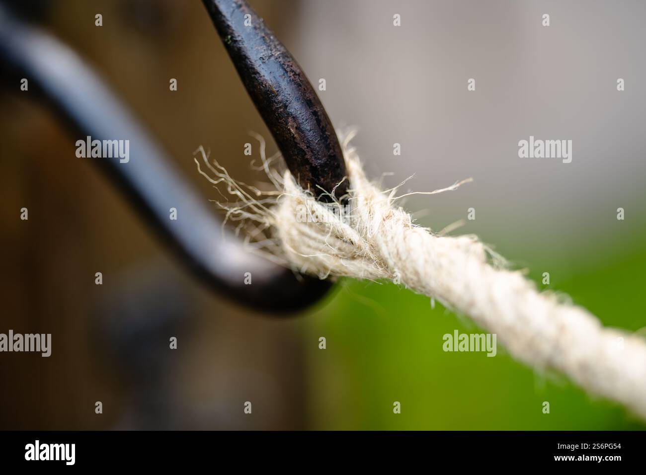 A rope is being pulled by a hook, and the rope is frayed. The rope is ...