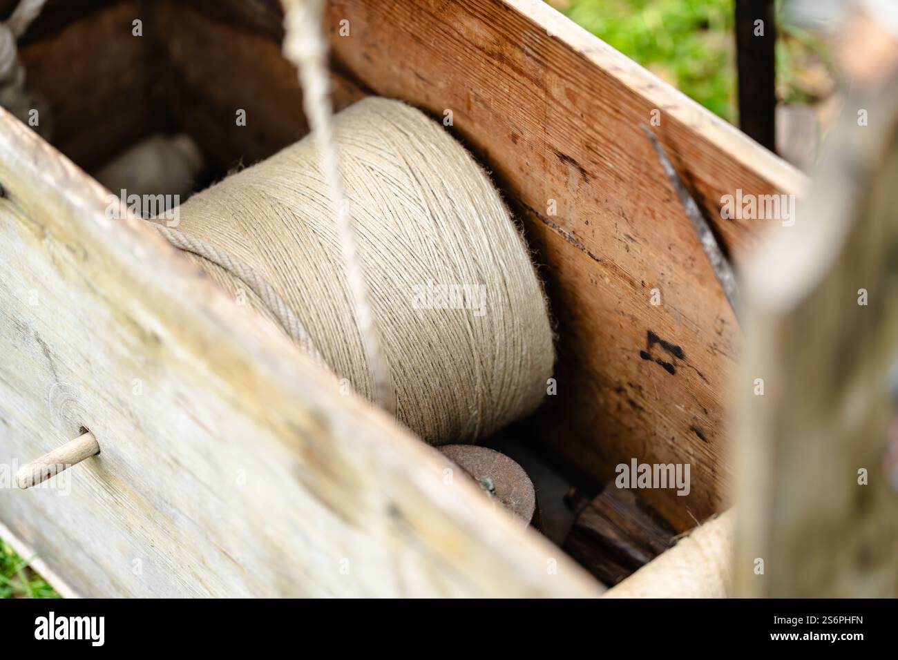 A wooden box with a white lid and a white rope inside. The rope is tied ...