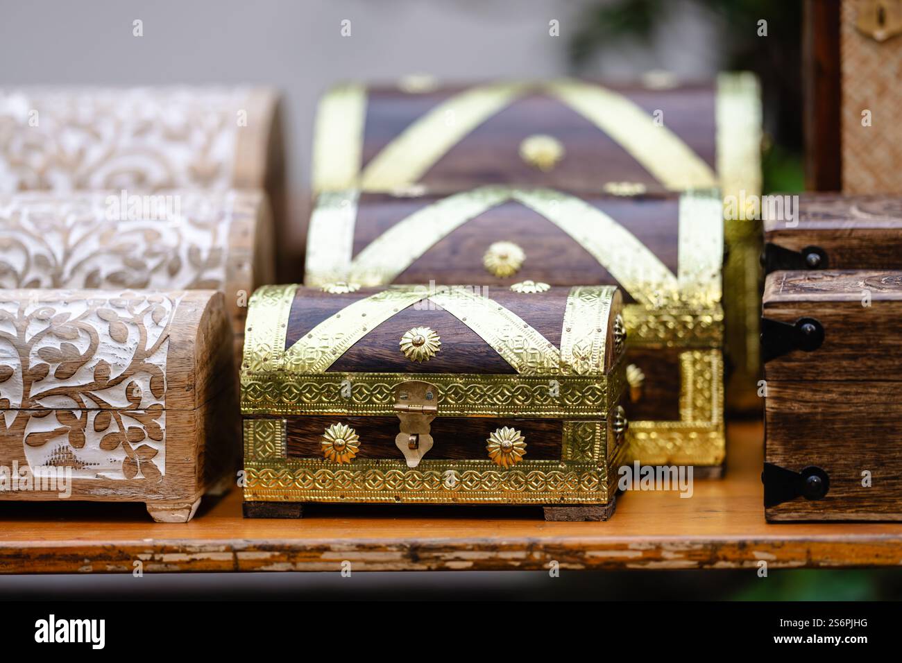 Three wooden chests with gold trim sit on a shelf. The chests are of ...
