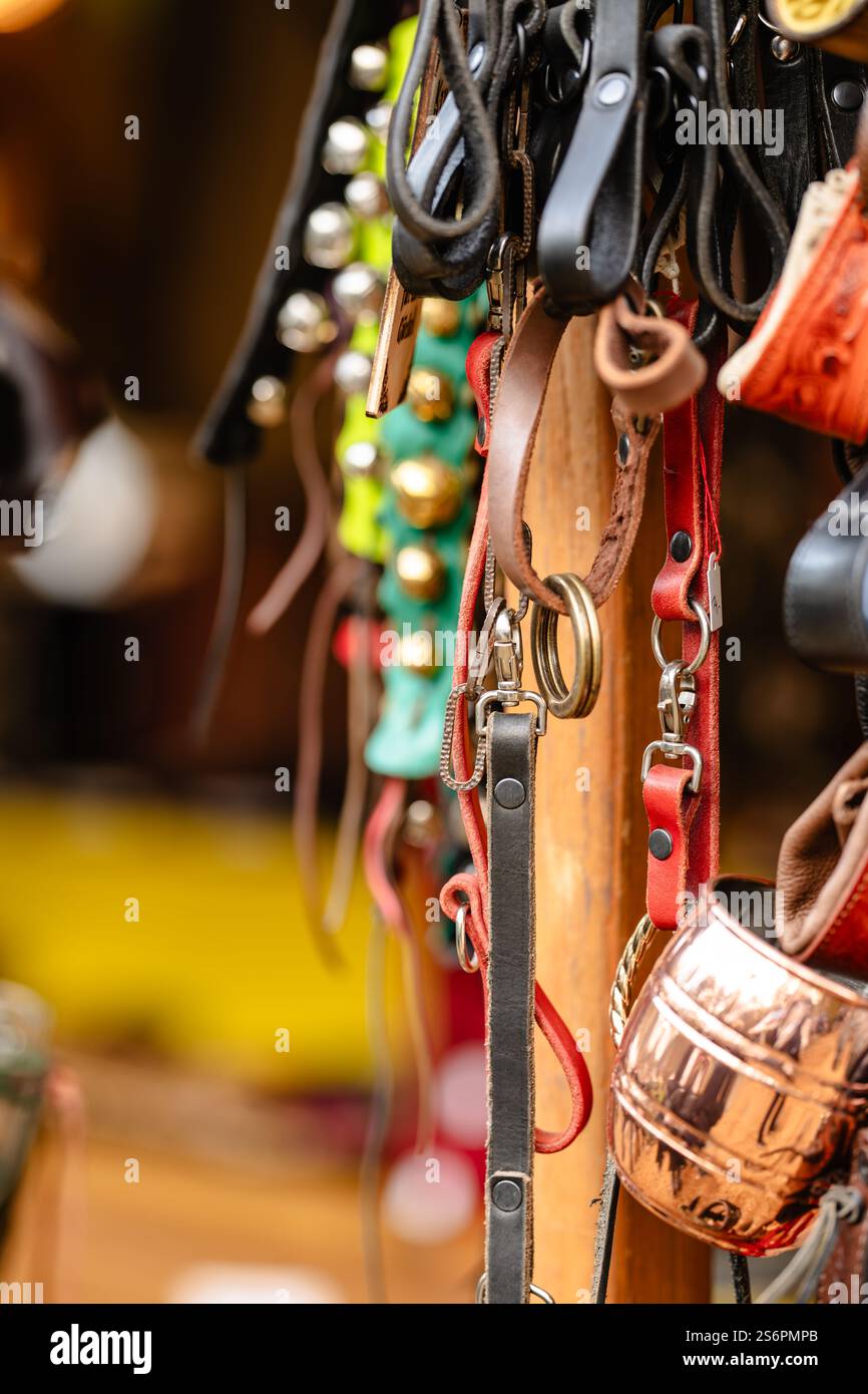 A collection of leather straps and buckles hanging on a rack. The ...