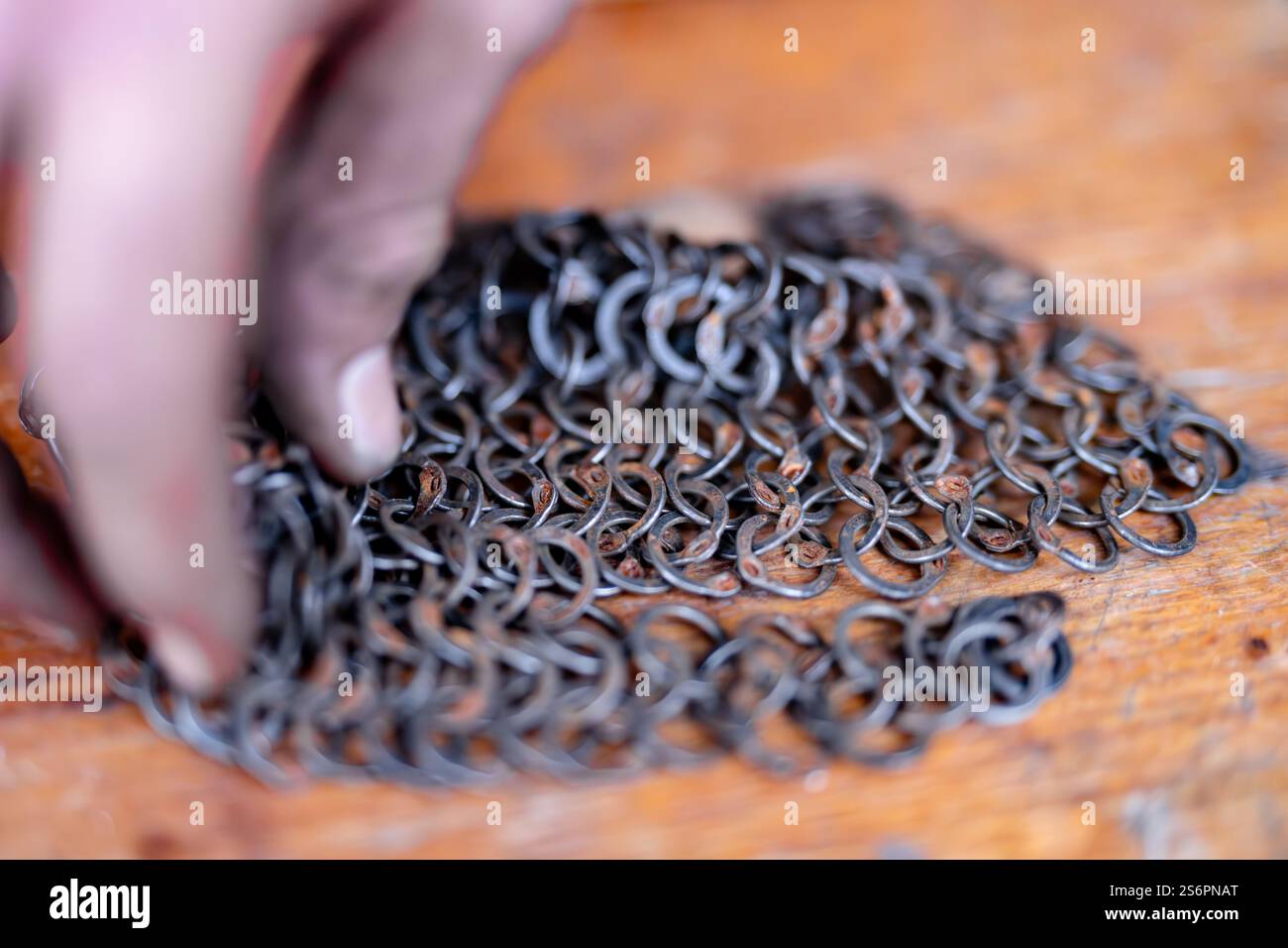 A hand is touching a chain of metal rings. The chain is made of metal ...