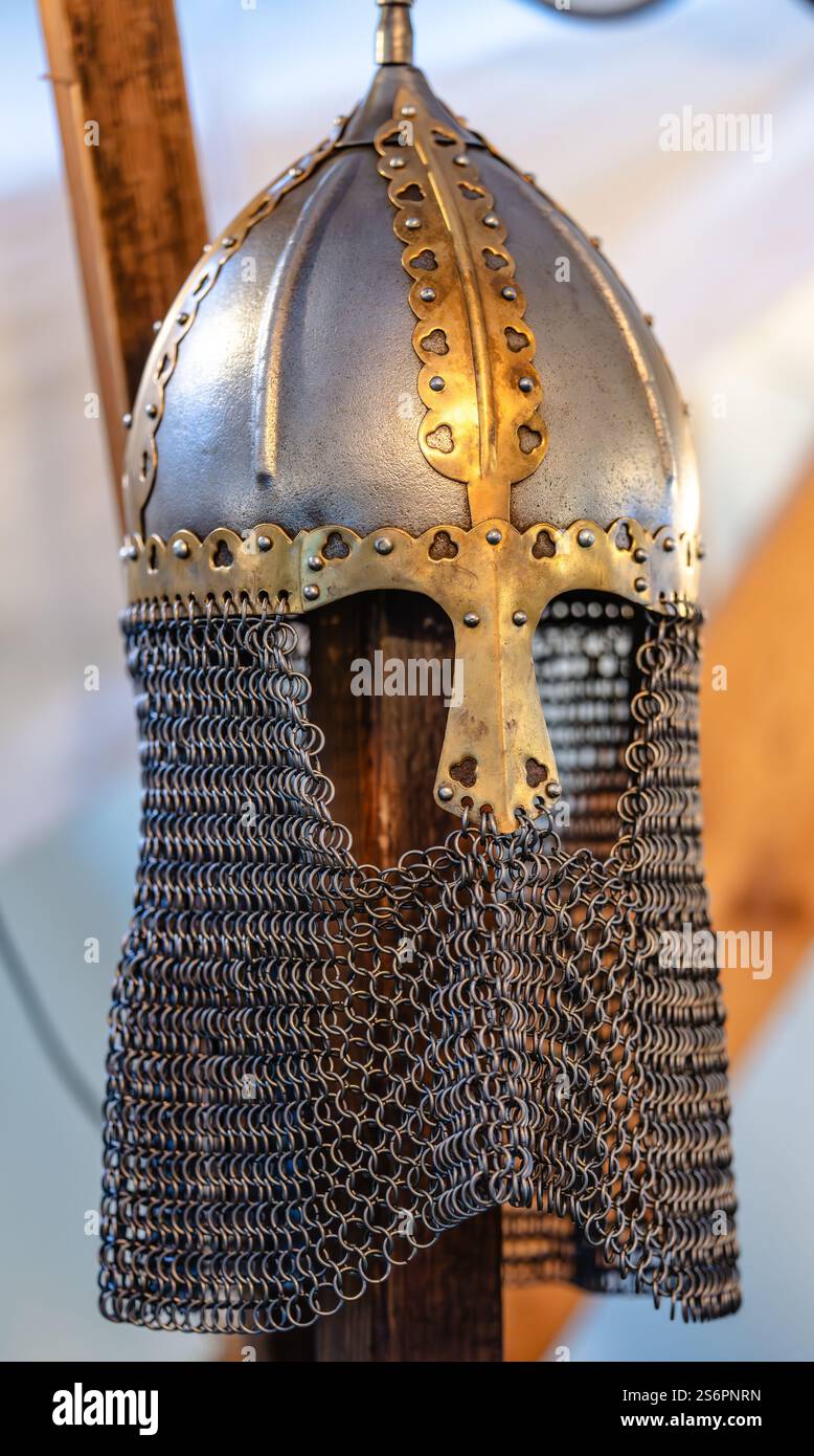 A helmet with a gold trim and a silver mesh. The helmet is hanging from ...
