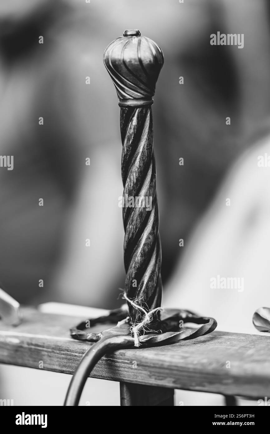 A sword with a twisted handle is shown in black and white. The sword is ...