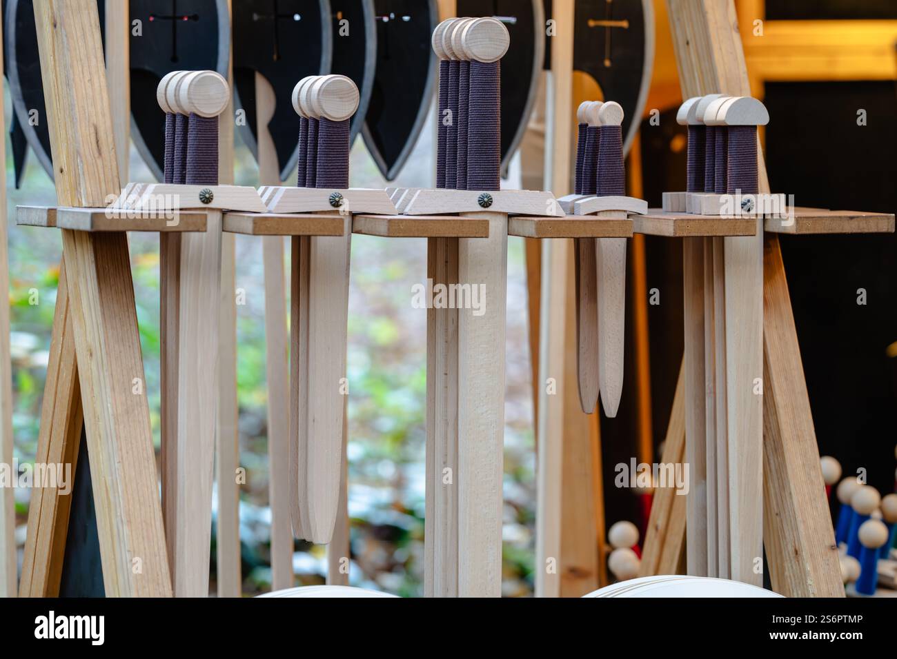 A wooden display of swords with a black background. The swords are ...