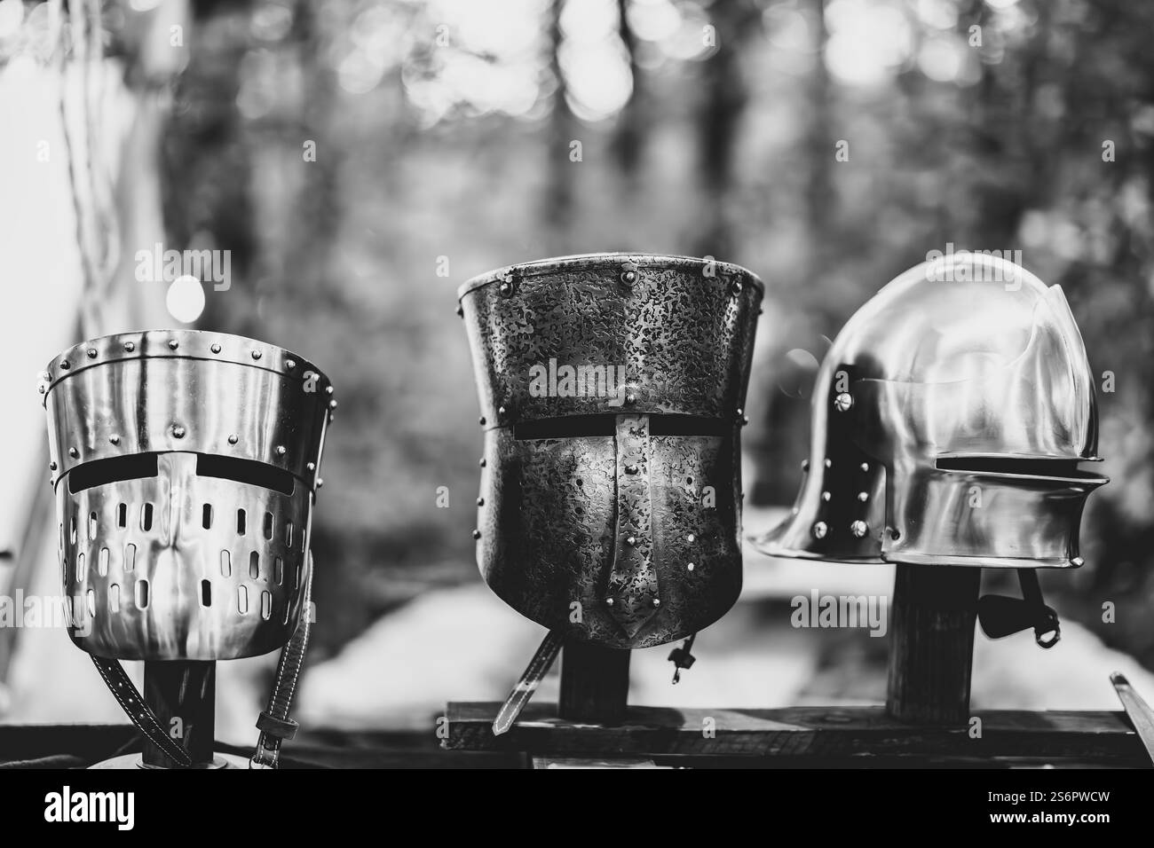 Three metal helmets are displayed on a wooden post. The helmets are old ...