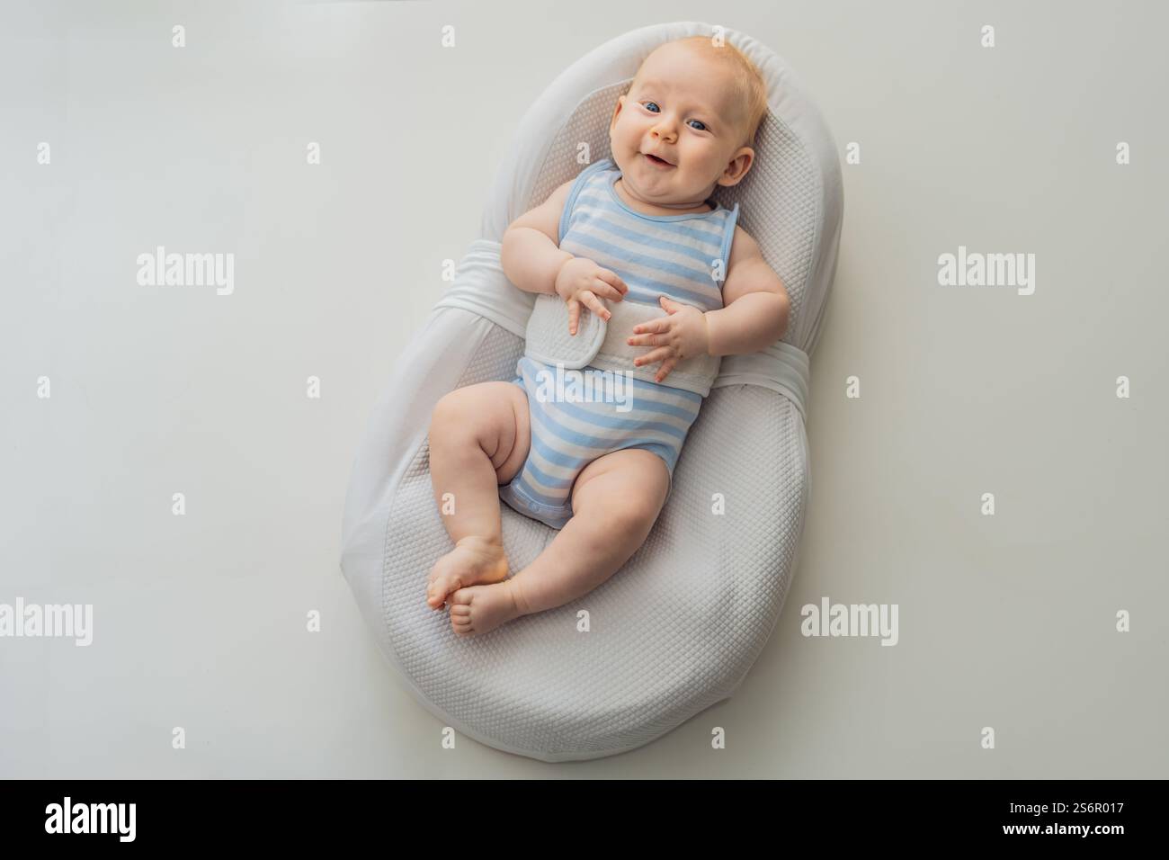 Adorable 3-month-old baby lying safely in a cozy infant cocoon secured ...