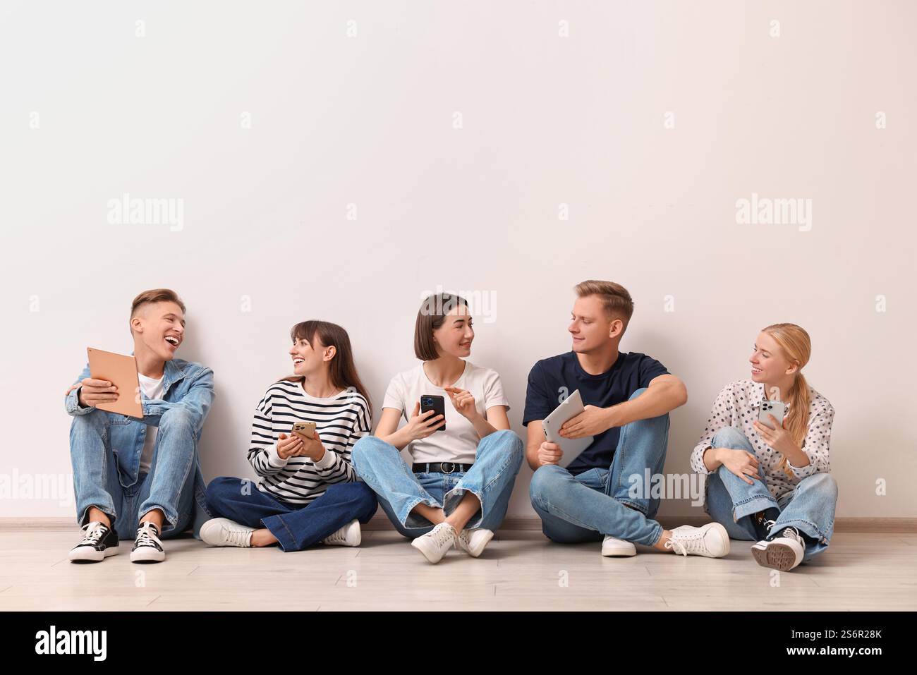 Group of people using different gadgets near white wall indoors. Modern ...