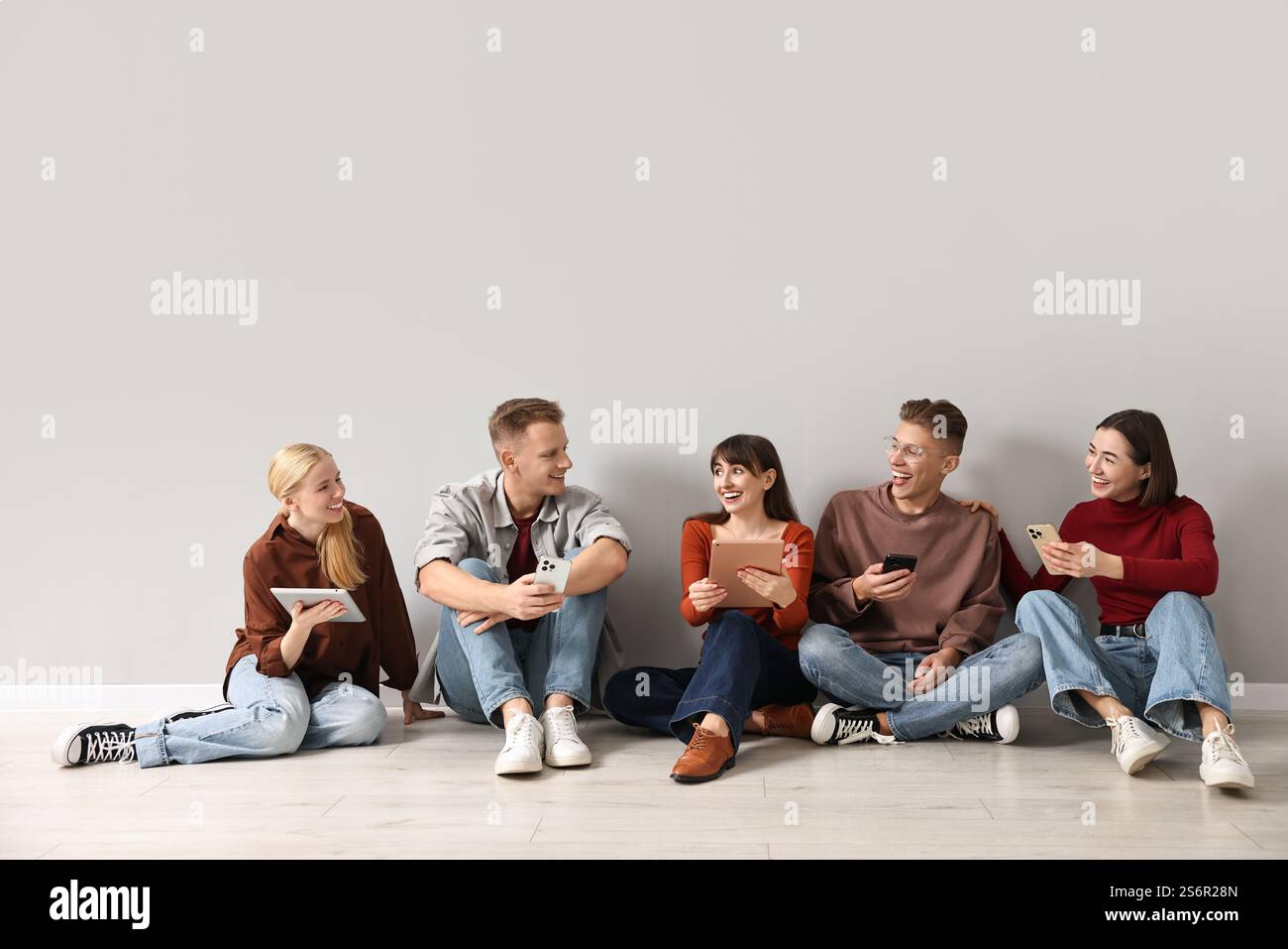 Group of people using different gadgets near light grey wall indoors ...