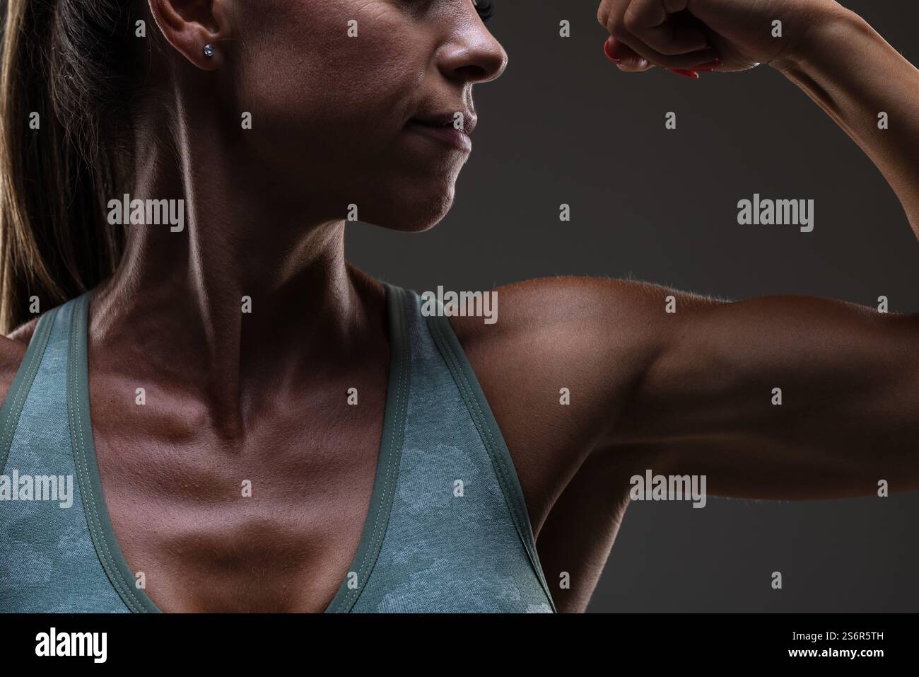 Portrait of a strong female athlete showing toned upper arm muscles in ...