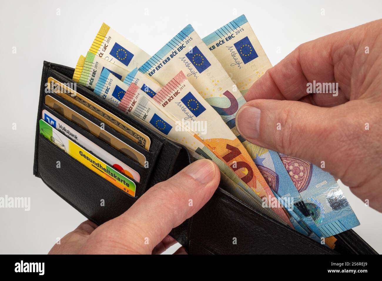 A man's hand pulls a 20 euro bill out of a black man's wallet, white ...