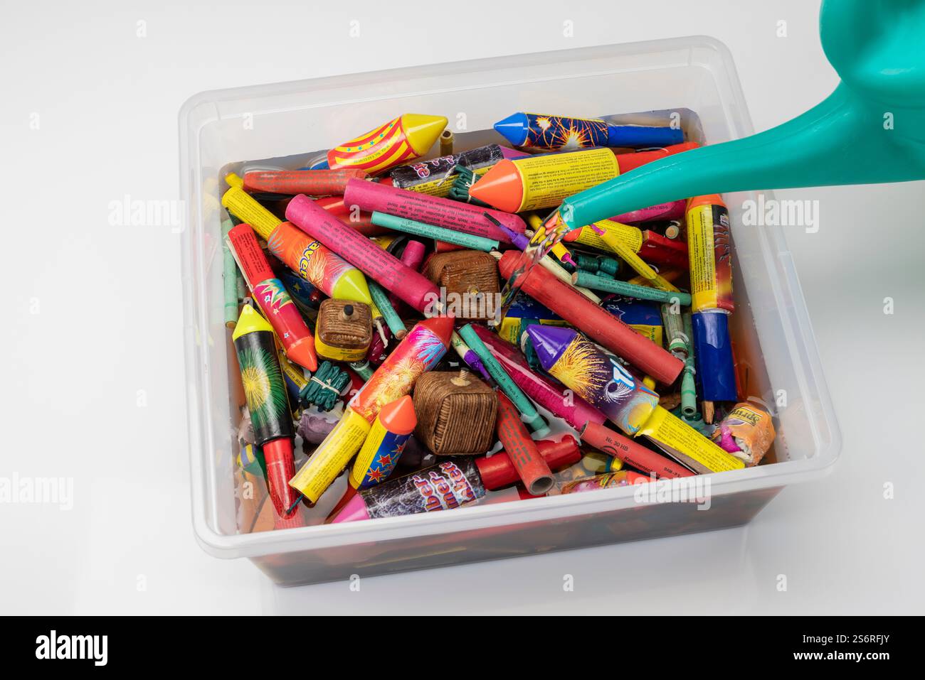 Unused fireworks in water-filled container, green watering can, white ...