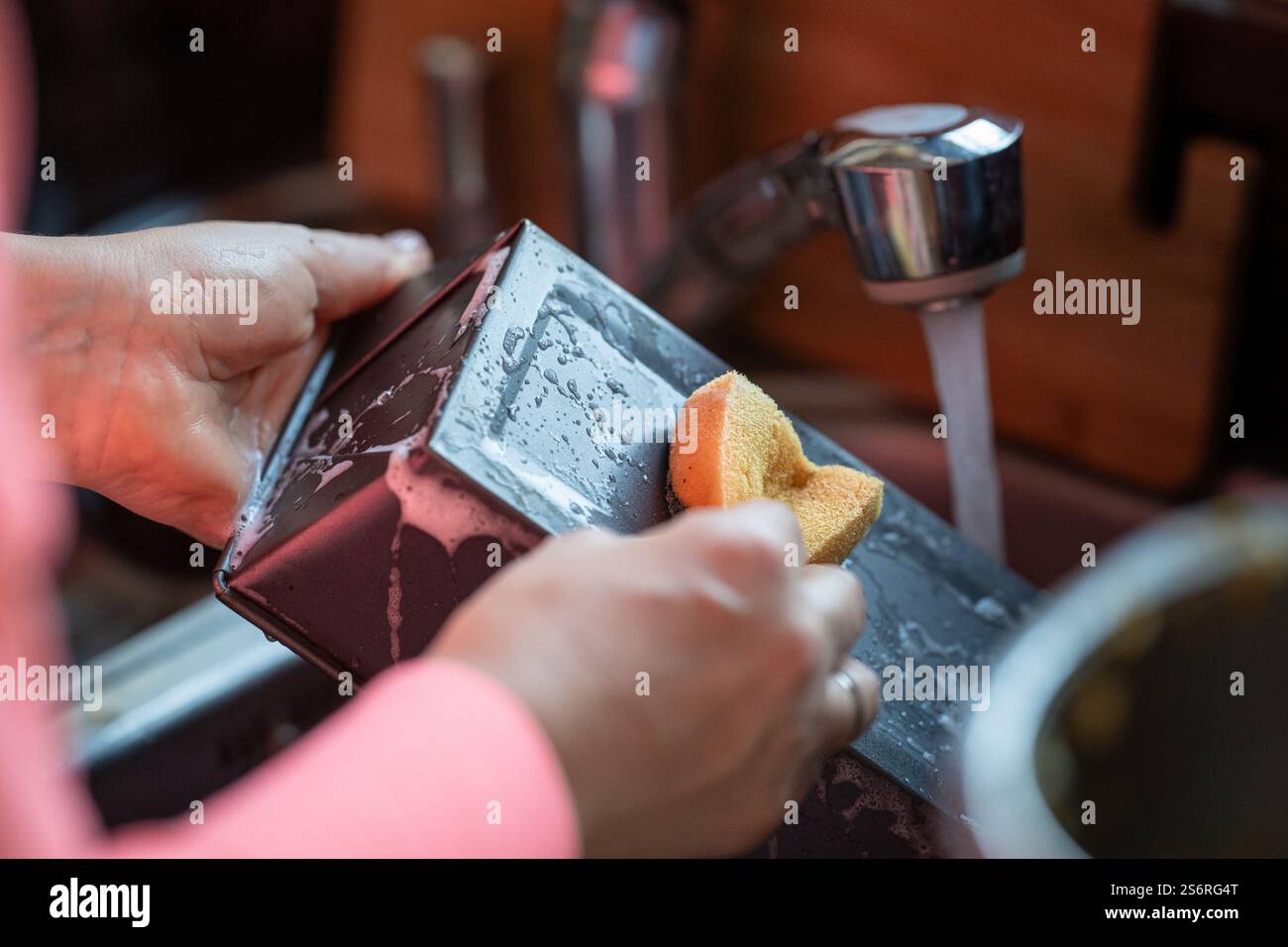 Hand wash the baking pan under running water Stock Photo - Alamy
