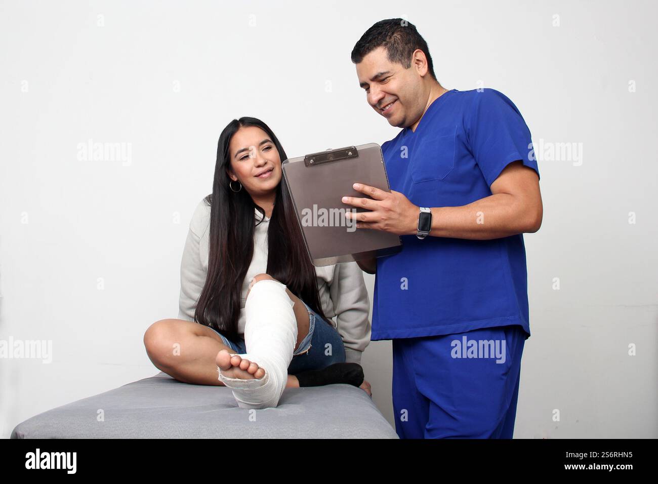 Woman with broken leg in a cast in the office of a dark-skinned Latino ...